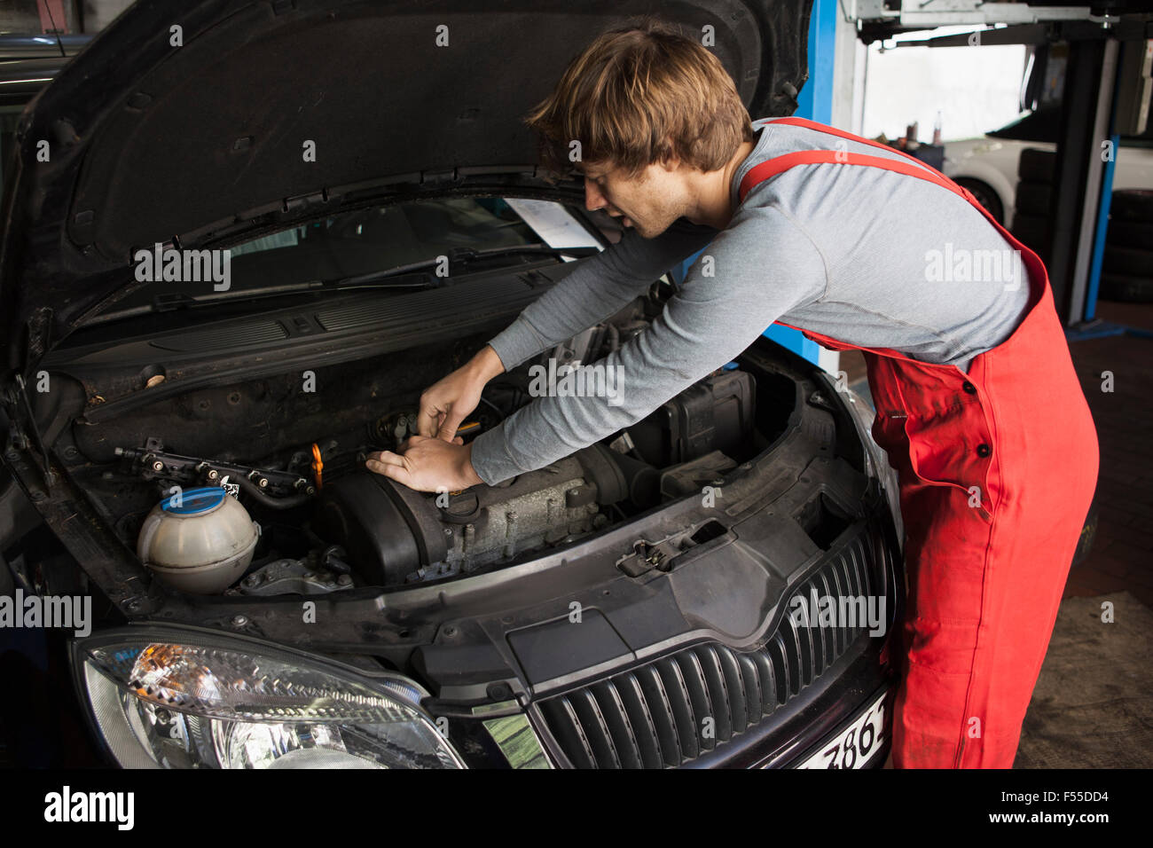 Mechanic examining car engine at workshop Stock Photo - Alamy