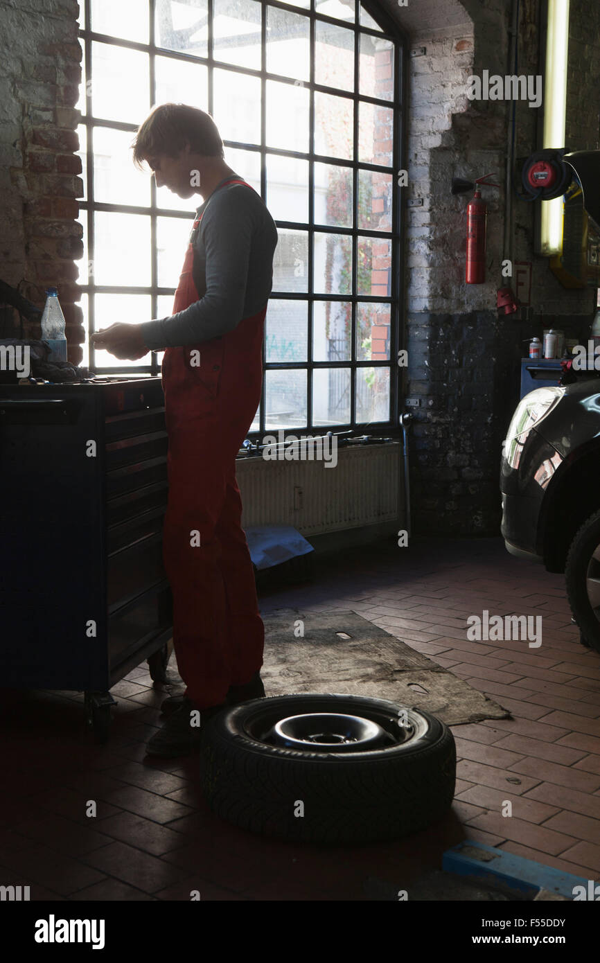 Side view of mechanic standing by window at garage Stock Photo - Alamy