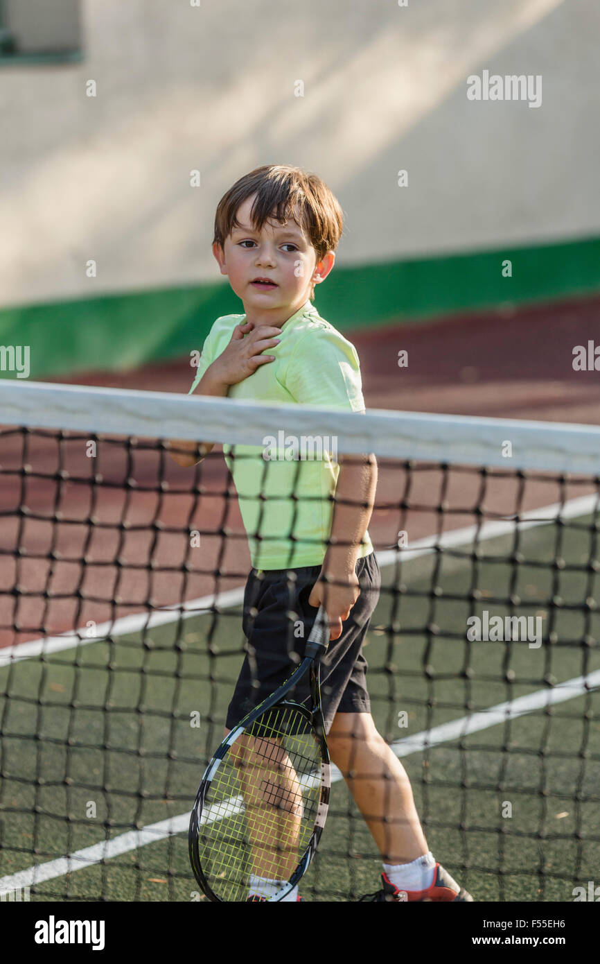 Boy holding tennis racket while standing on field Stock Photo - Alamy