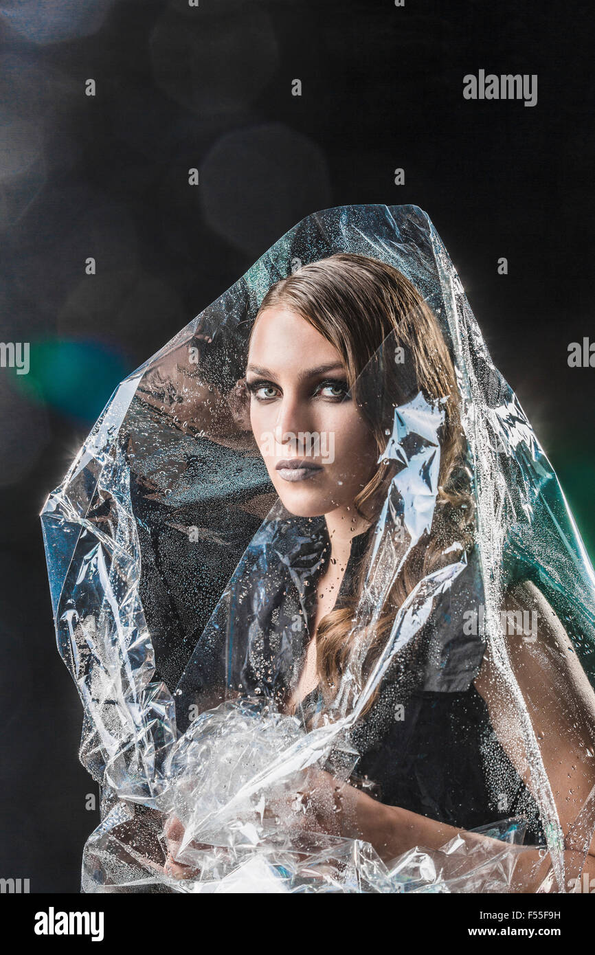 Portrait of confident woman wrapped in plastic against black background Stock Photo - Alamy