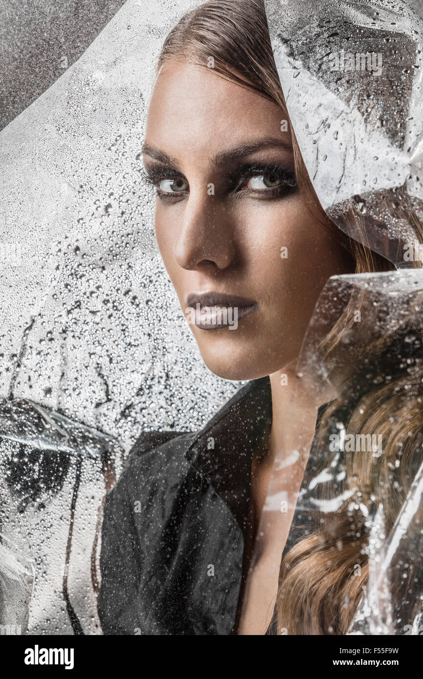 Portrait of beautiful woman wrapped in plastic against black background Stock Photo - Alamy