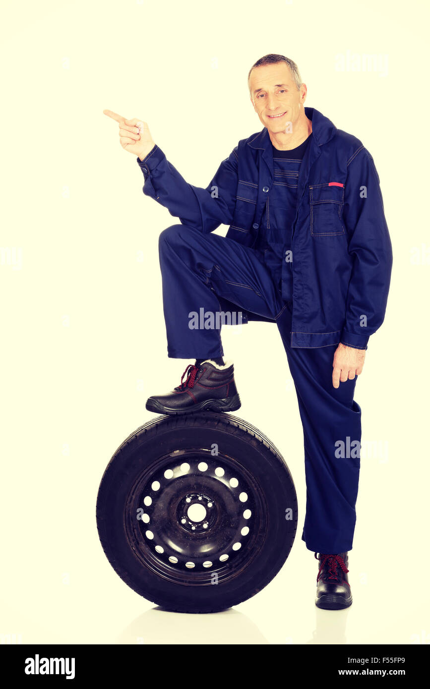 Mechanic with leg on a tire pointing to the left Stock Photo - Alamy