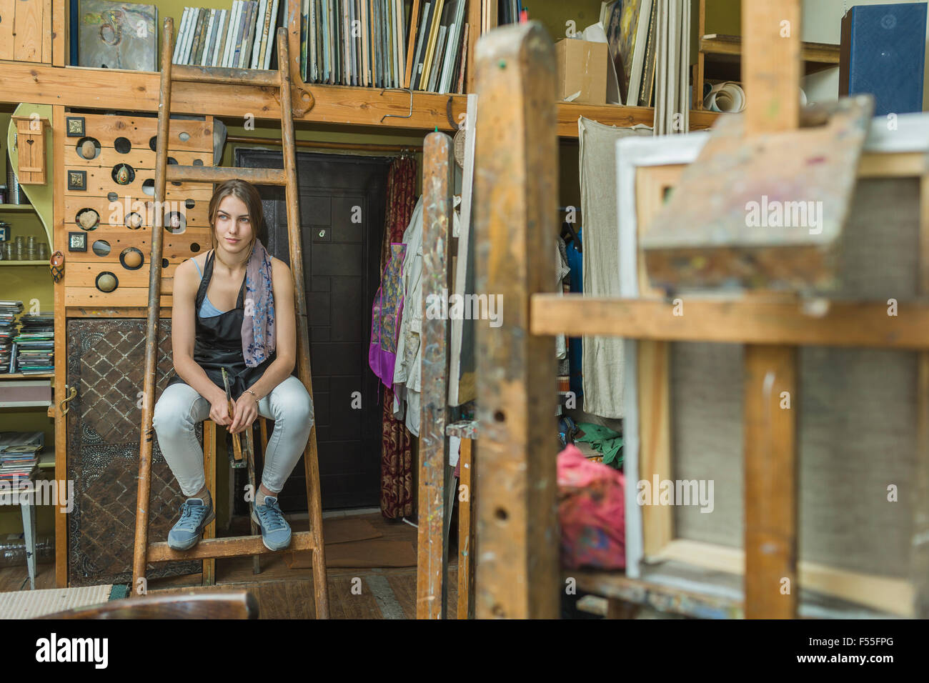 Female artist sitting on ladder in art studio Stock Photo - Alamy