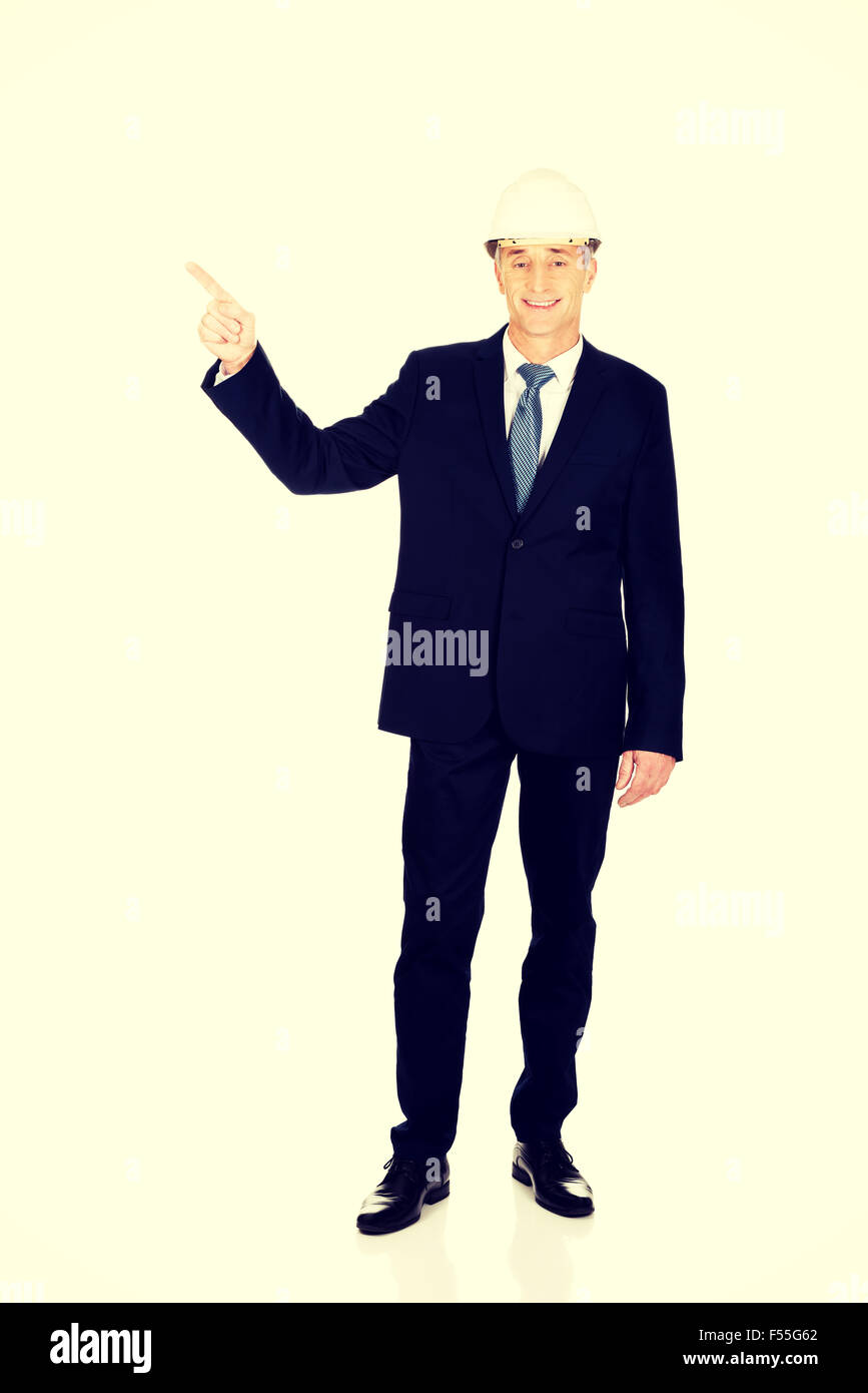 Smiling businessman with hard hat pointing up Stock Photo - Alamy