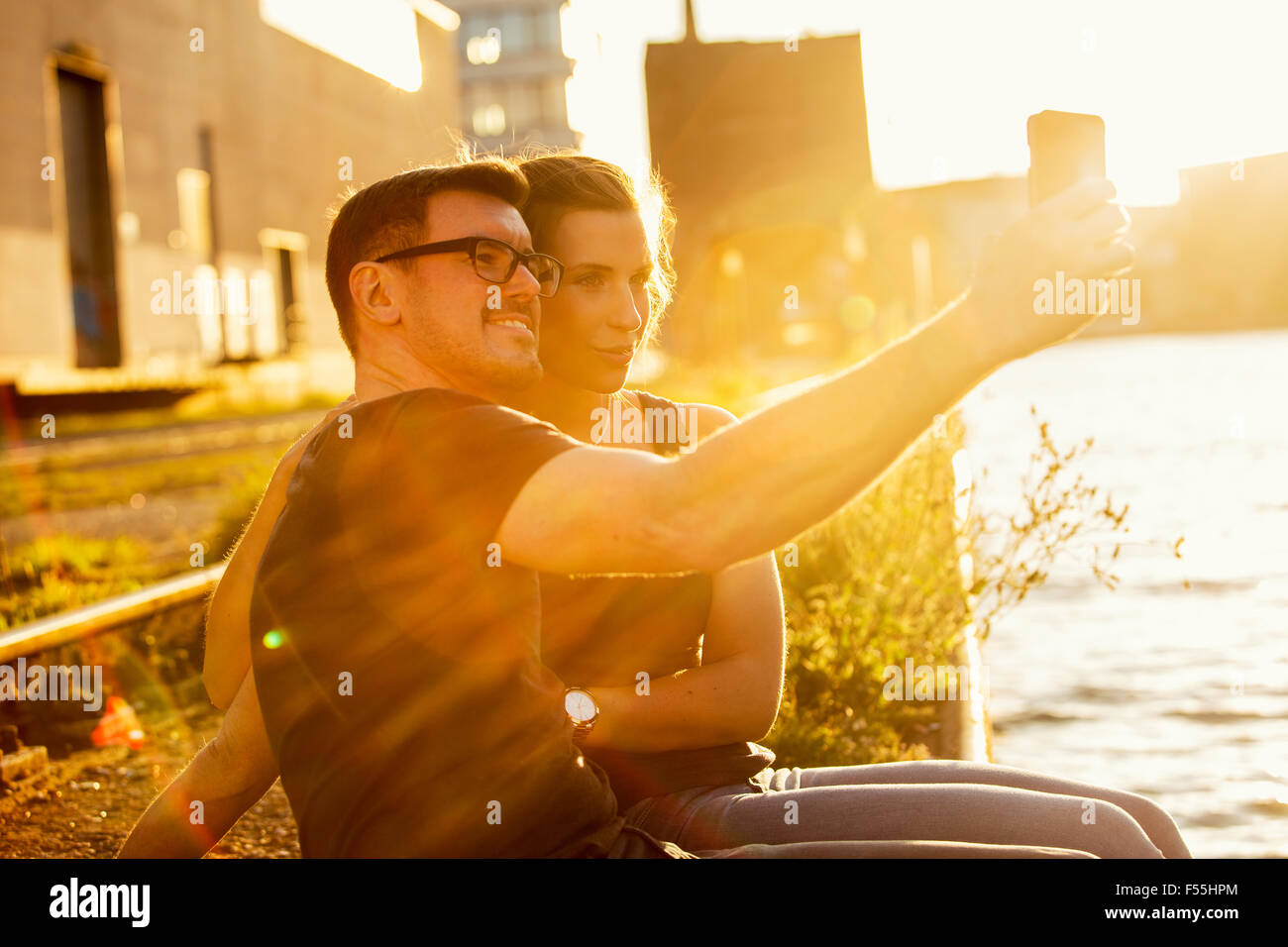 Germany, Muenster, couple taking a selfie with smartphone at backlight ...