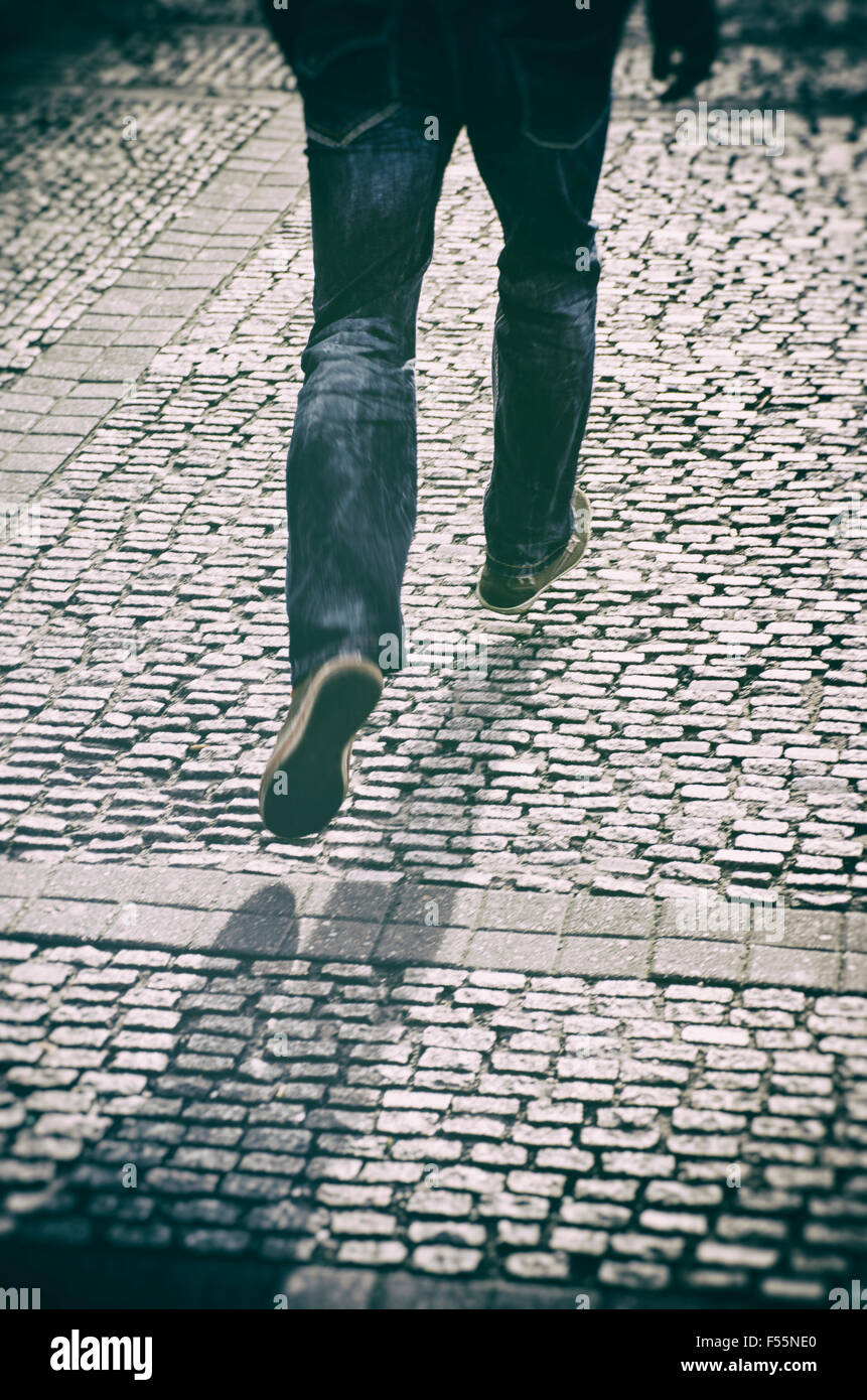 Mysterious man running on a cobbled street Stock Photo - Alamy