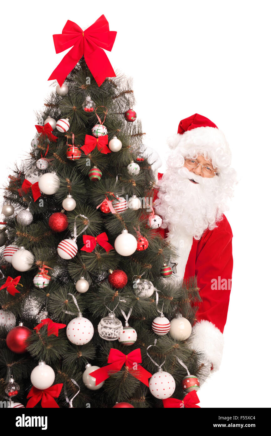 Vertical shot of Santa Claus standing behind a Christmas tree and ...