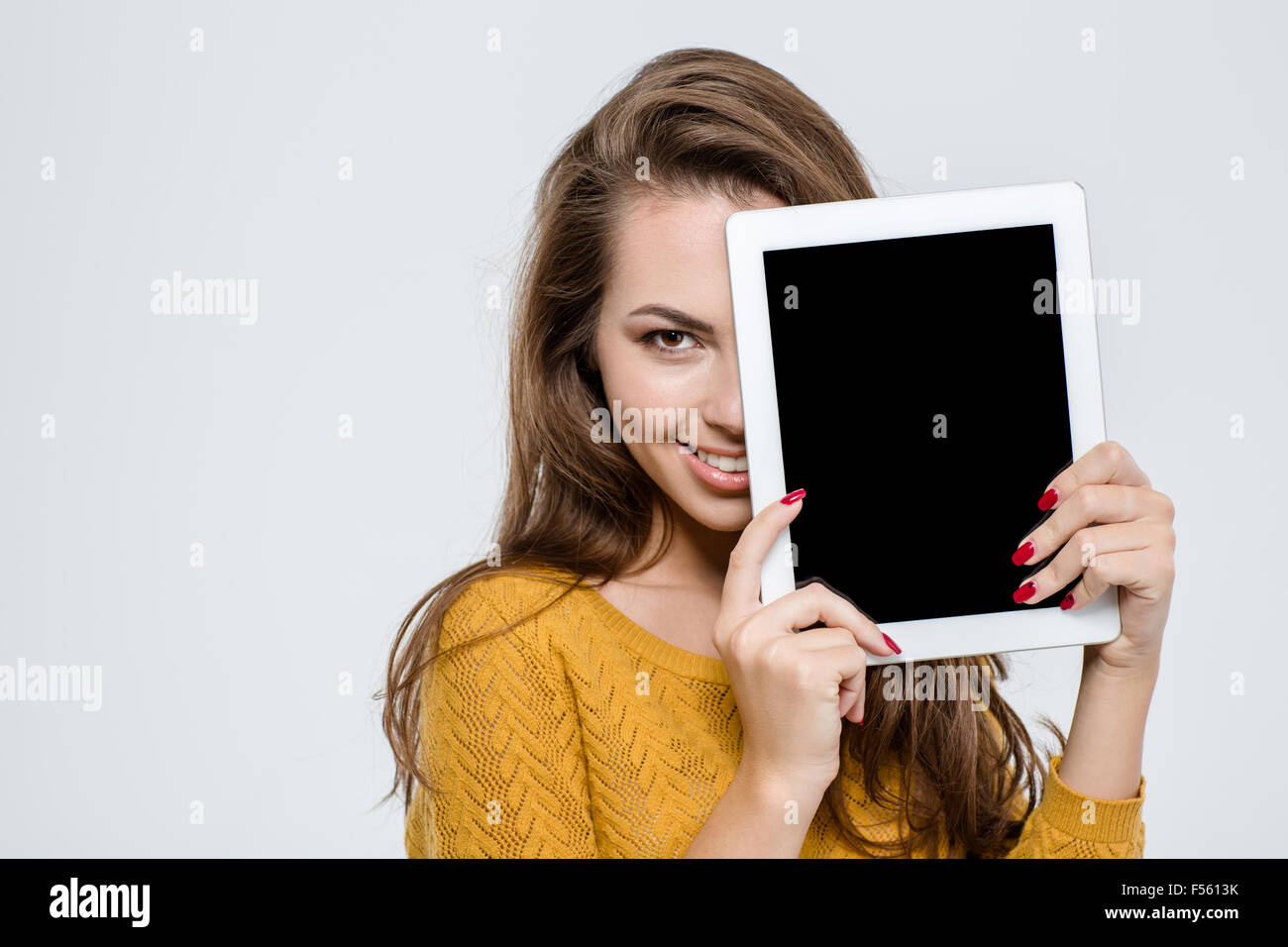 Portrait of a happy cute woman covering half face with tablet computer ...