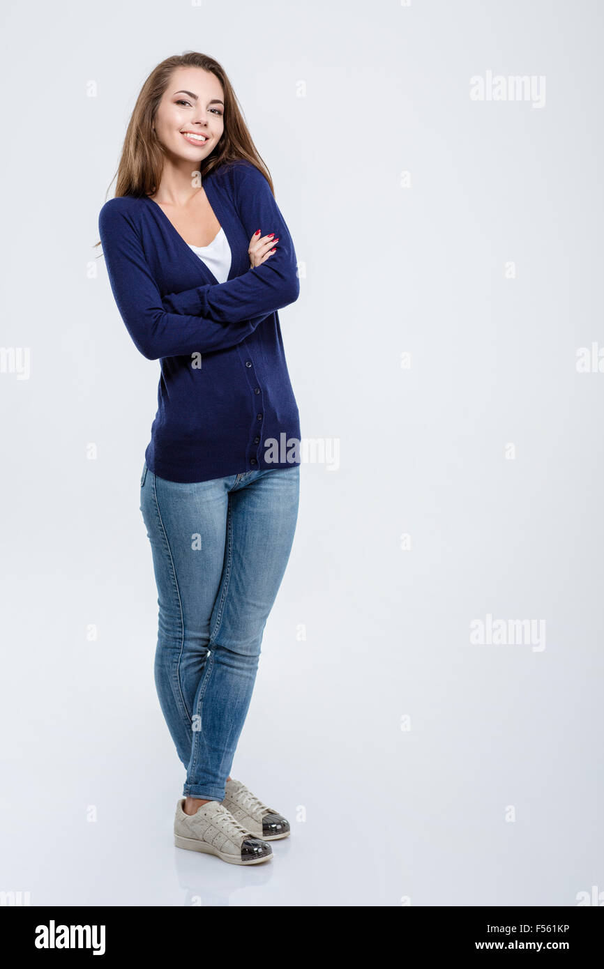 Full length portrait of a happy woman standing with arms folded ...