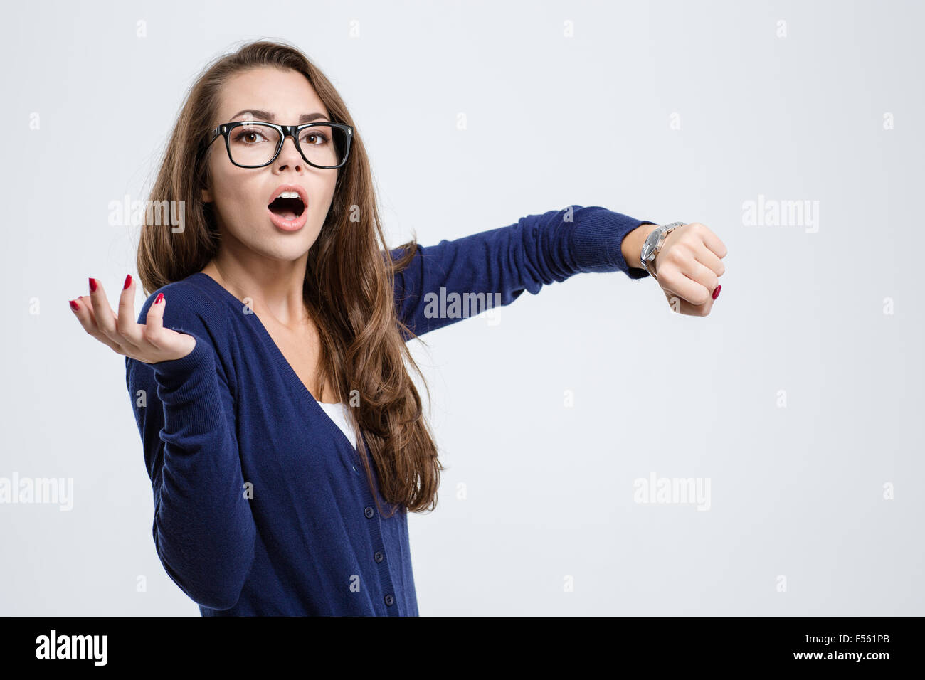 Portrait of a shocked woman holding hand with wrist watch and looking ...