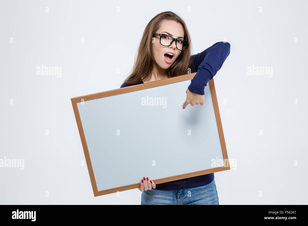 Portrait of a cute beautiful woman pointing finger on blank board ...