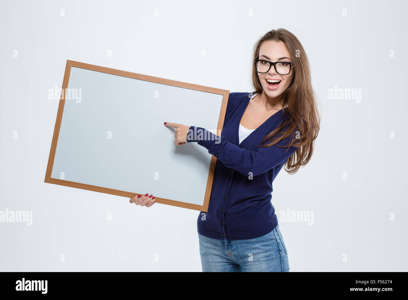 Portrait of a cheerful woman pointing finger on blank board isolated on ...