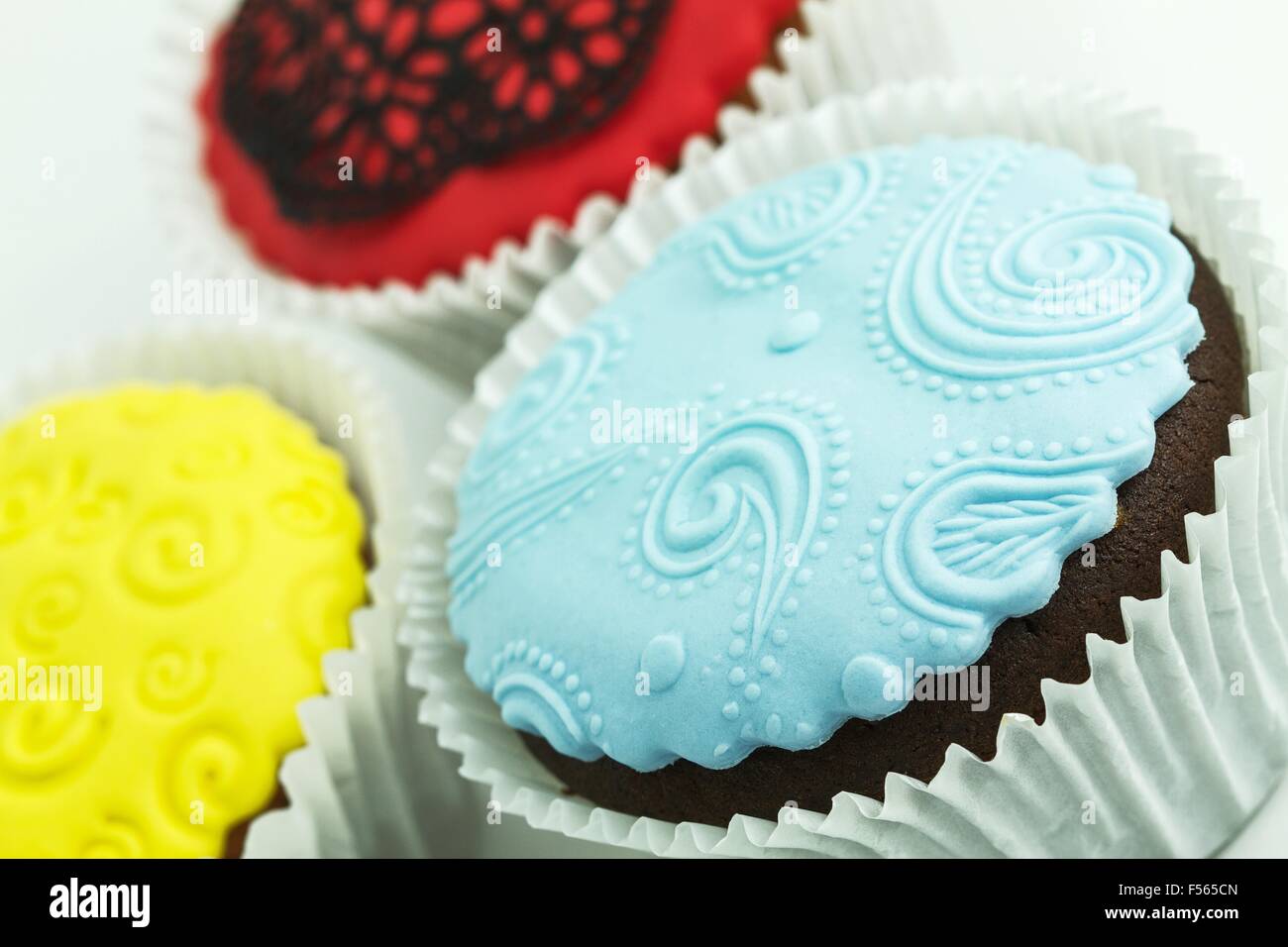 Three cupcakes on the white background. Yellow, blue and red with ...