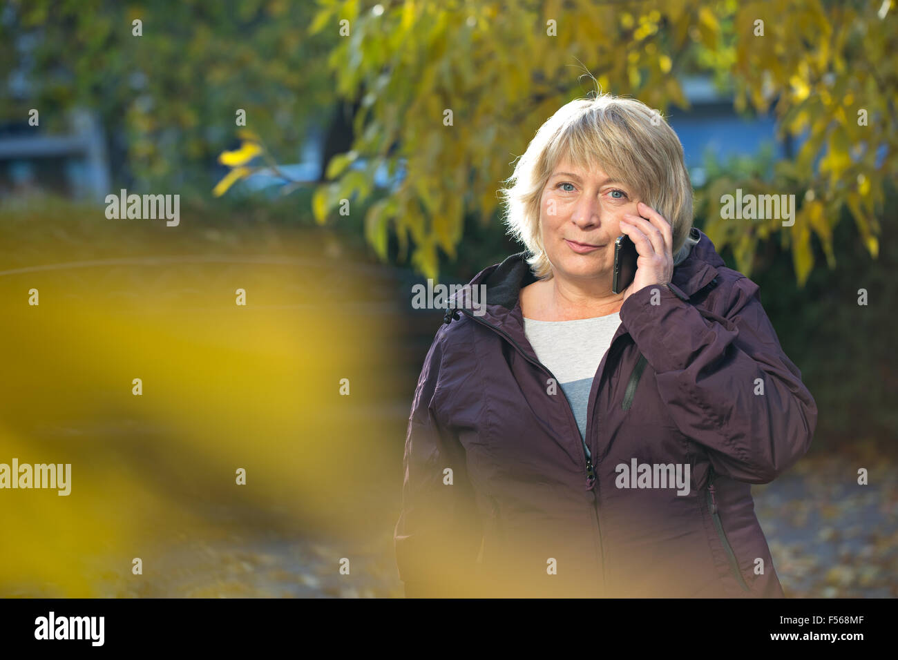 Happy beautiful woman calling by phone in autumn street Stock Photo - Alamy