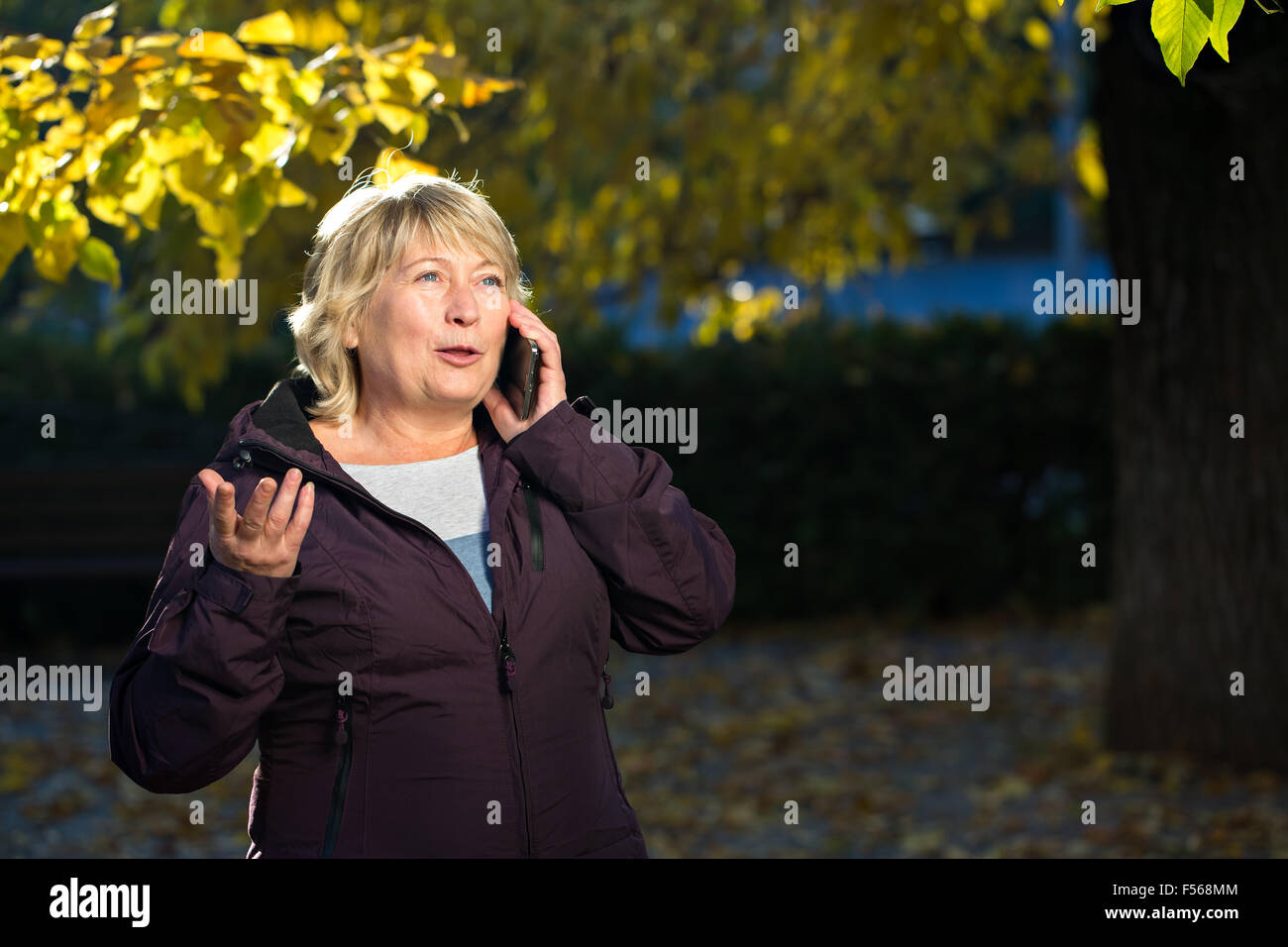Happy beautiful woman calling by phone in autumn street Stock Photo - Alamy