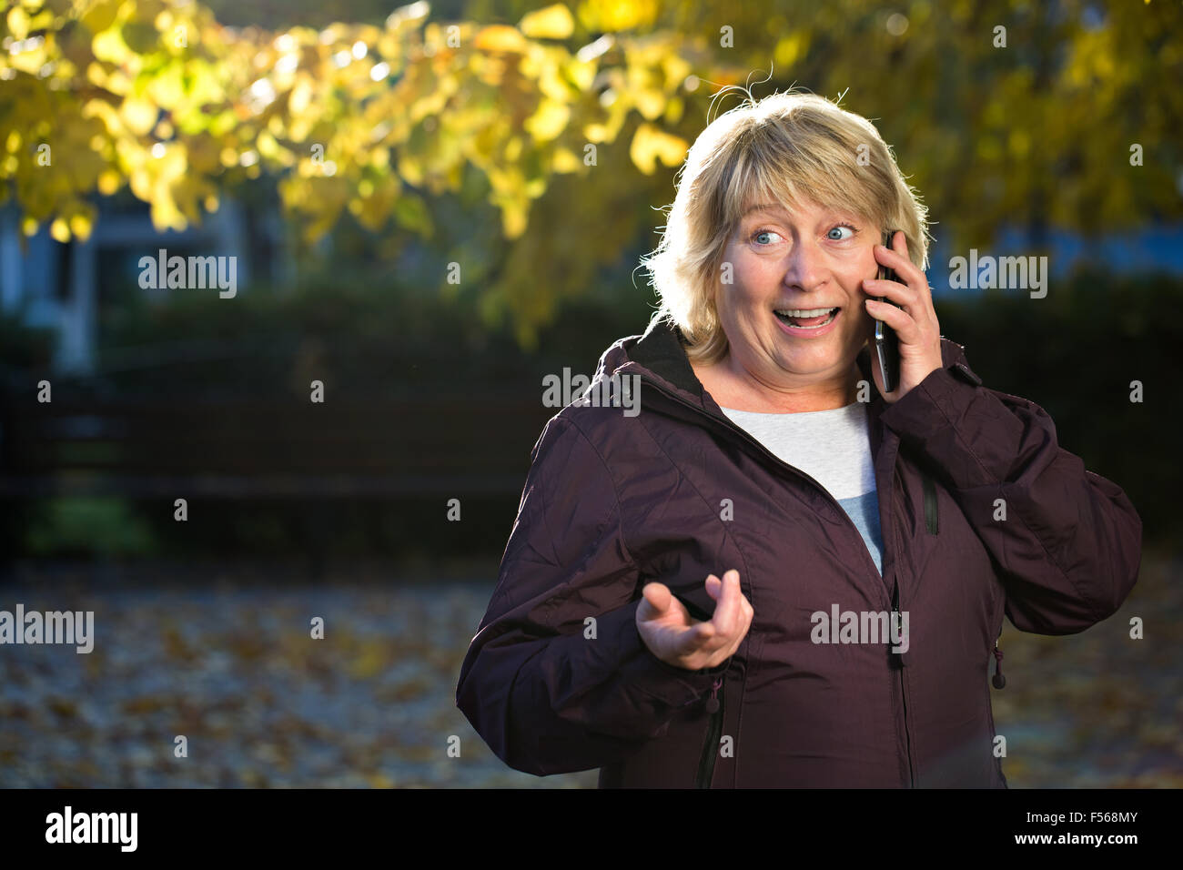 Happy beautiful woman calling by phone in autumn street Stock Photo - Alamy
