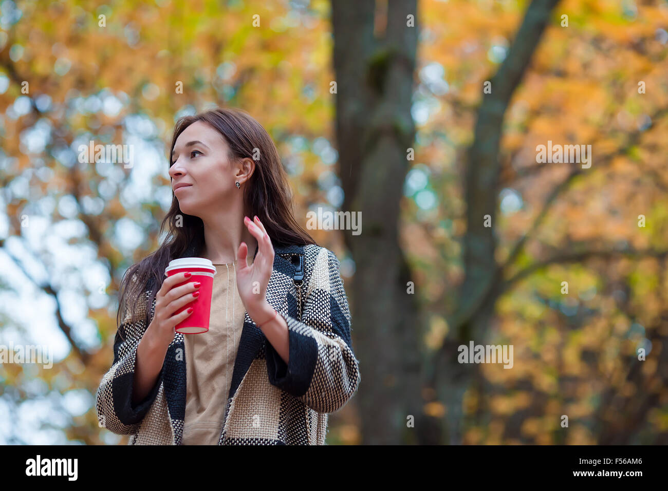 Fall concept - beautiful woman drinking coffee in autumn park under ...