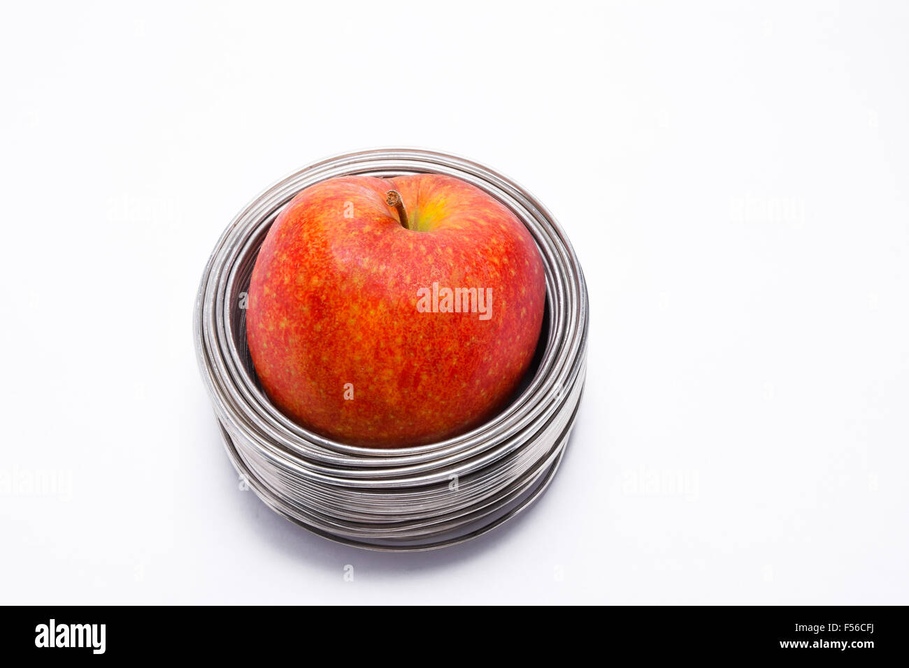 Wired apple: whole red apple in coils of aluminum wire isolated on ...