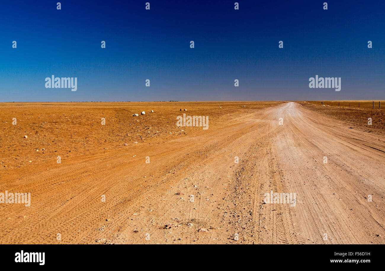 Long straight outback road through arid treeless landscape to distant ...