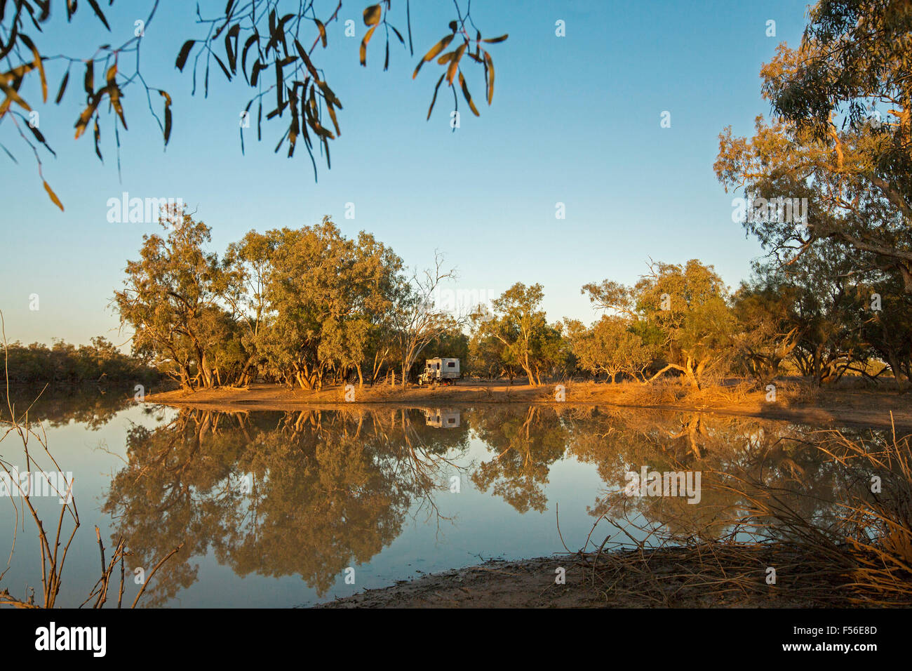 Paroo River with motorhome among trees & blue sky reflected in calm ...