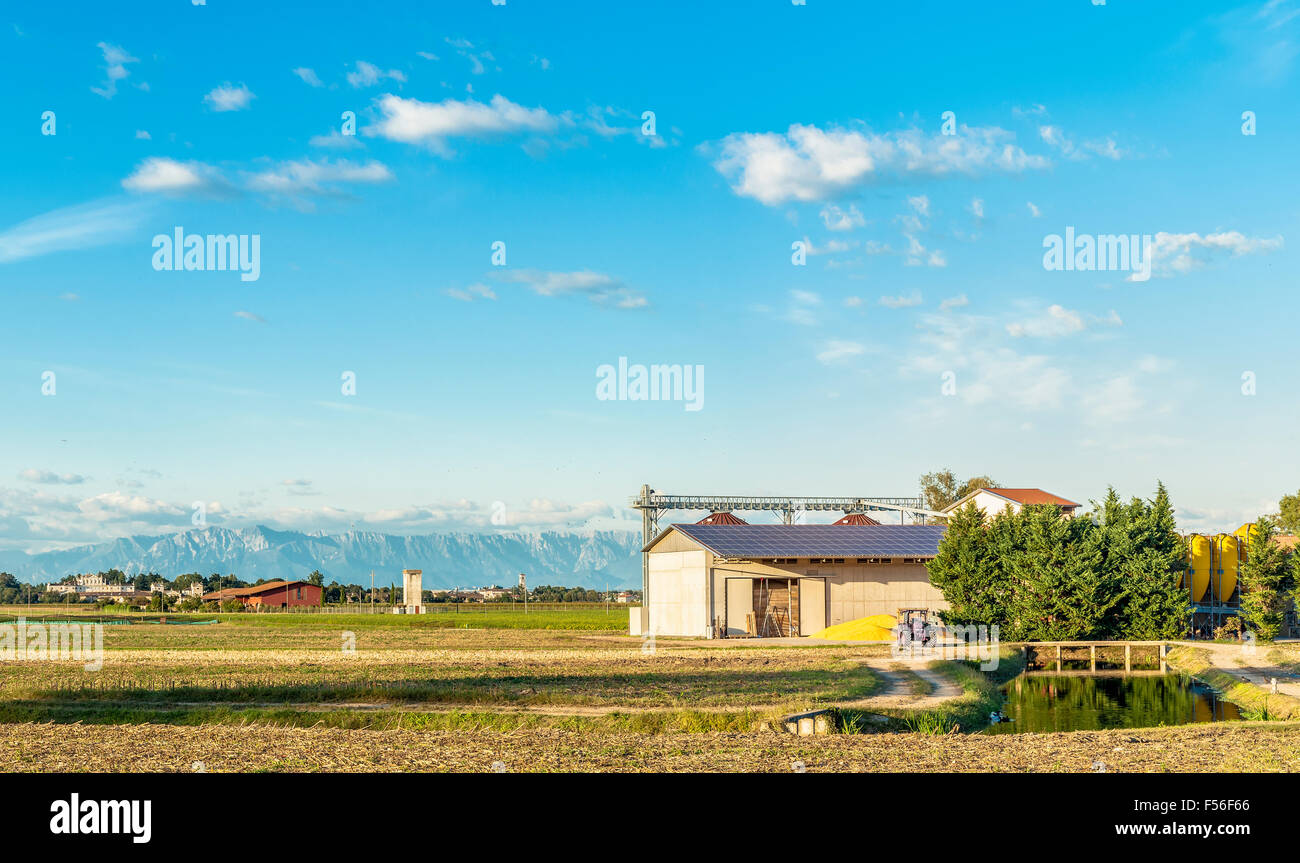 Agricultural landscape with river,mountains and farm with tractor and ...