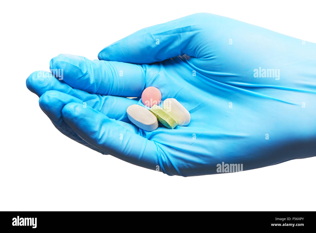 Close up of four white, pink and green tablets on female doctor's hand ...
