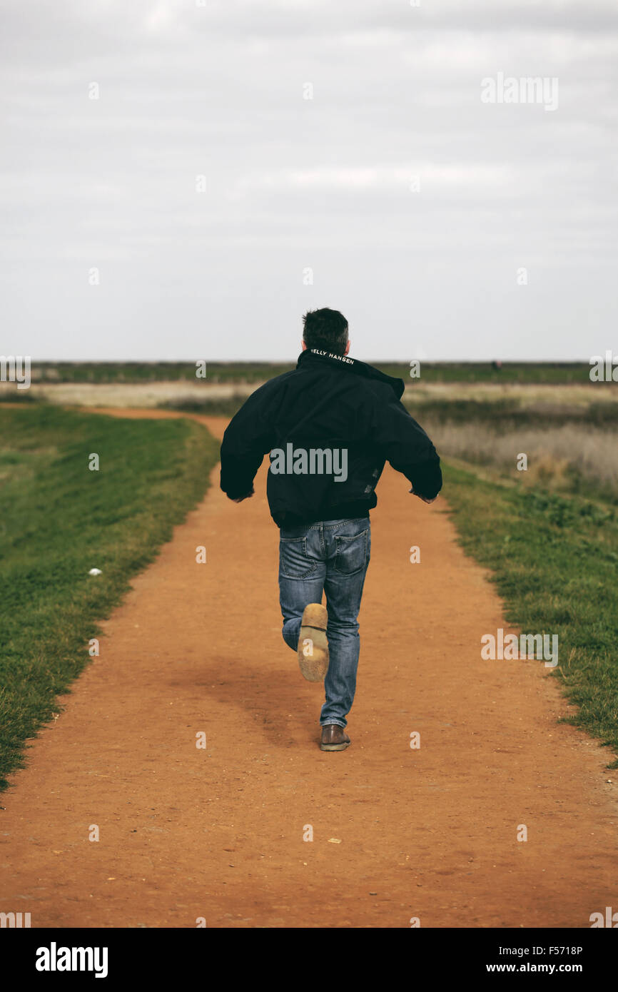Middle aged man running in rural coastal area Stock Photo - Alamy