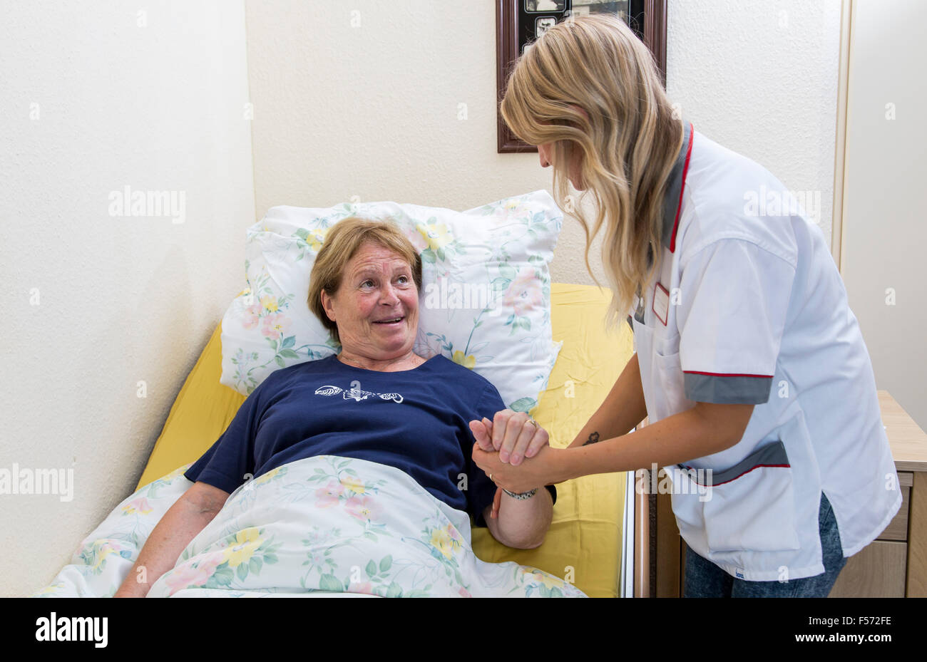 Elderly care in a nursing home, nurse helps an elderly woman in bed, in ...