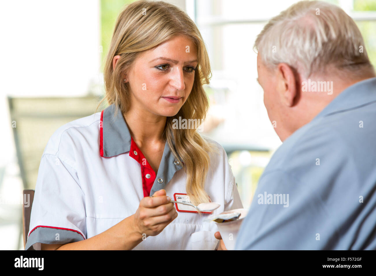 Elderly care in a nursing home, nurse helps an elderly man eating his ...
