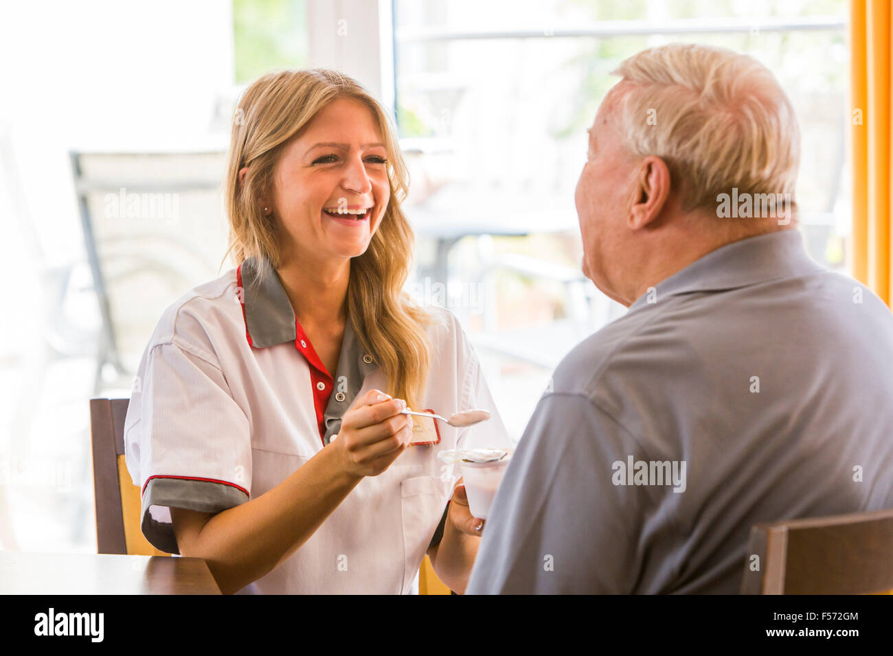 Elderly care in a nursing home, nurse helps an elderly man eating his ...