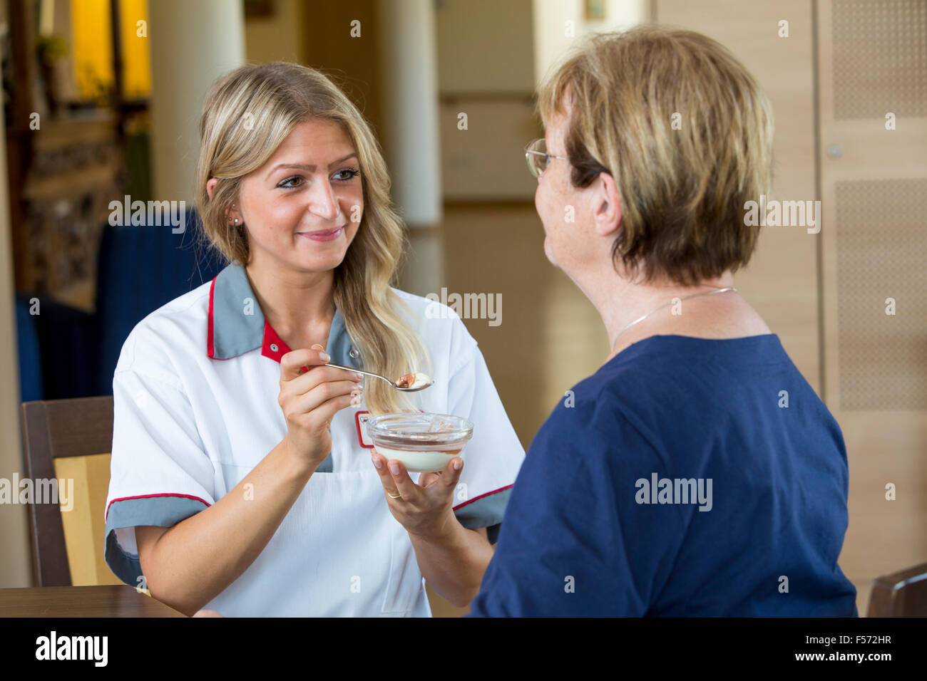 Elderly care in a nursing home, nurse helps an elderly woman eating her ...
