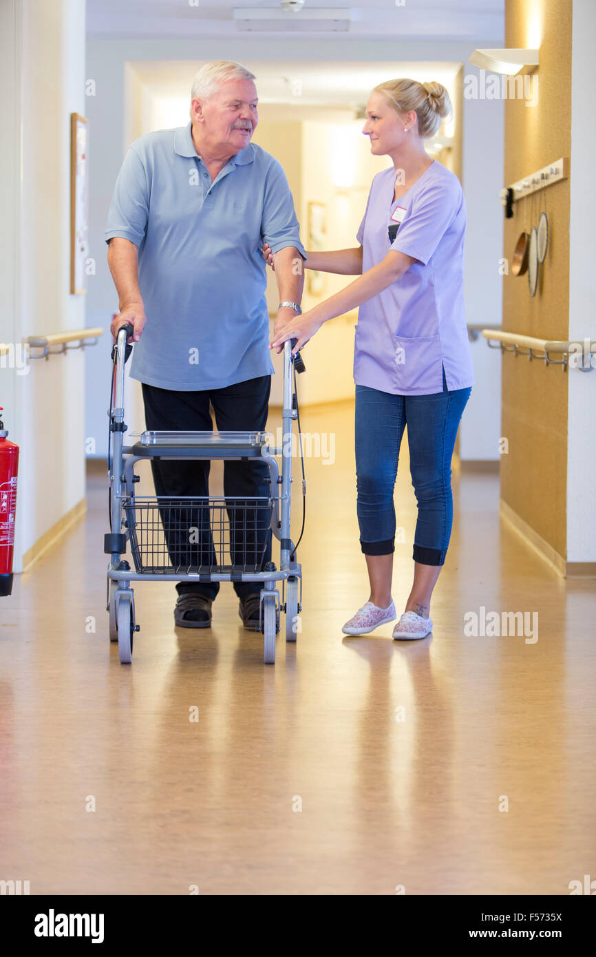 Elderly care in a nursing home, nurse helps an elderly man walking with ...
