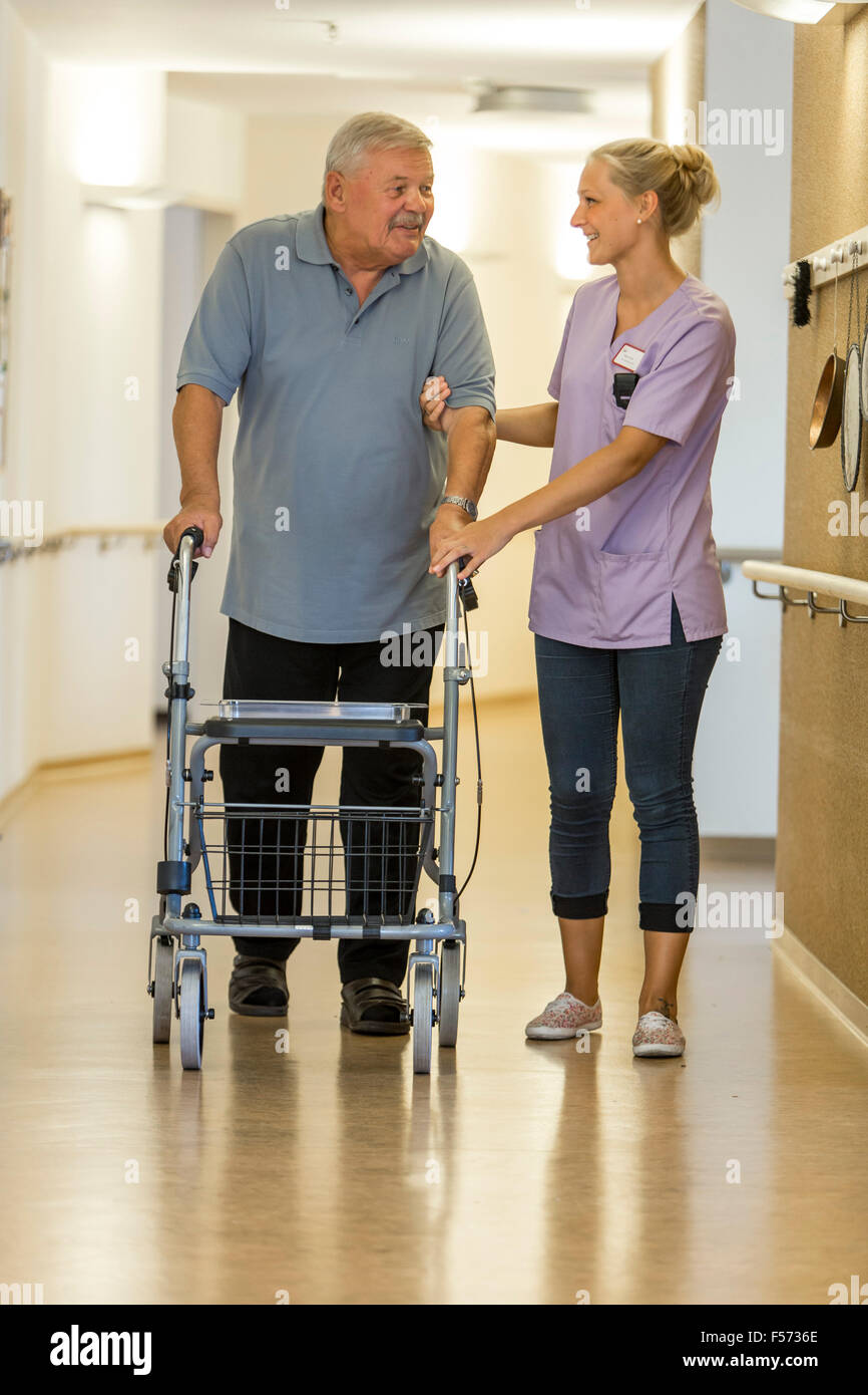 Elderly care in a nursing home, nurse helps an elderly man walking with ...
