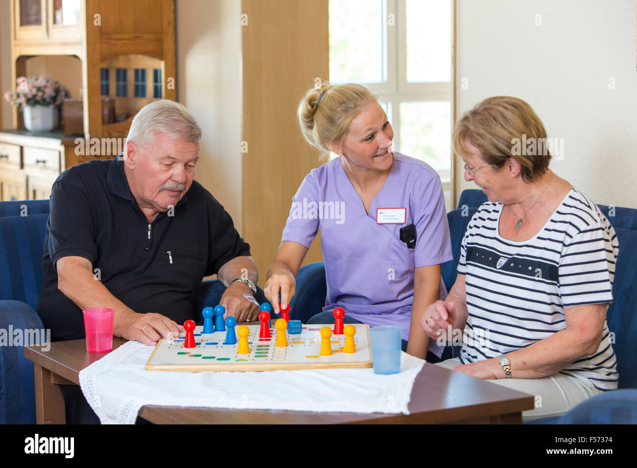 Elderly care in a nursing home, nurse plays with two patients a game ...