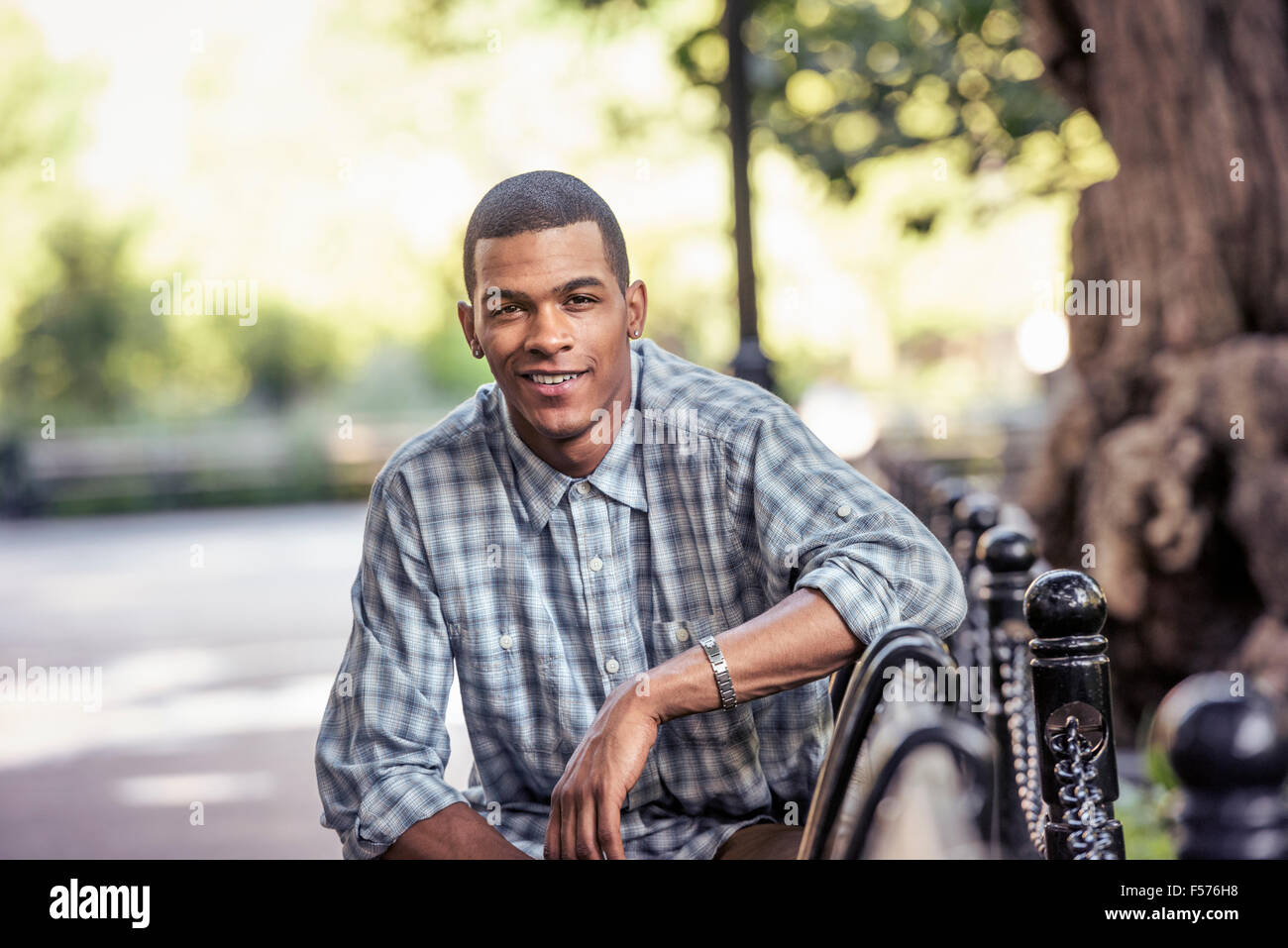 A man seated in a city park relaxing on a bench Stock Photo - Alamy