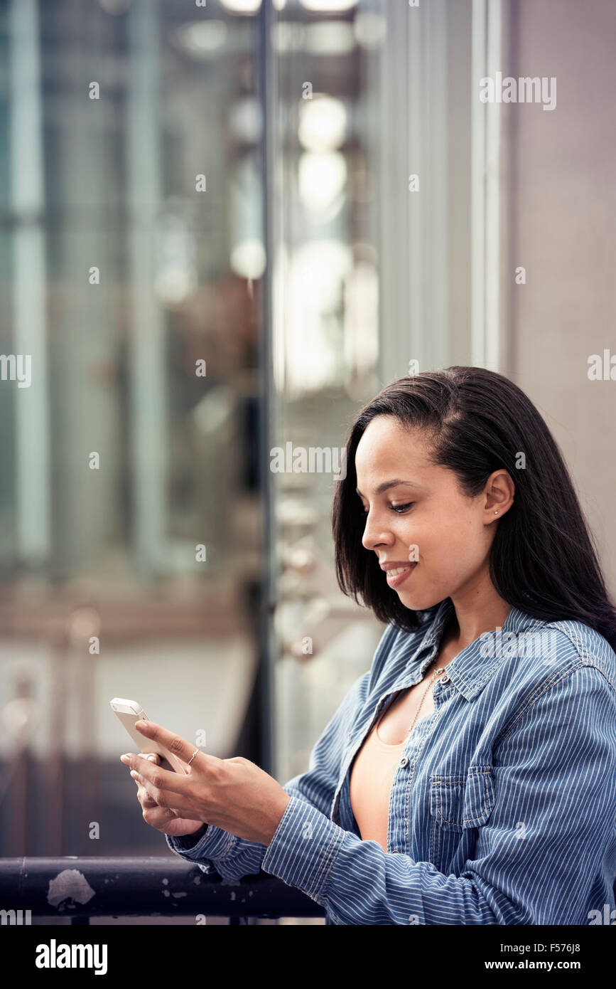 A young woman checking her cell phone on a city street Stock Photo - Alamy