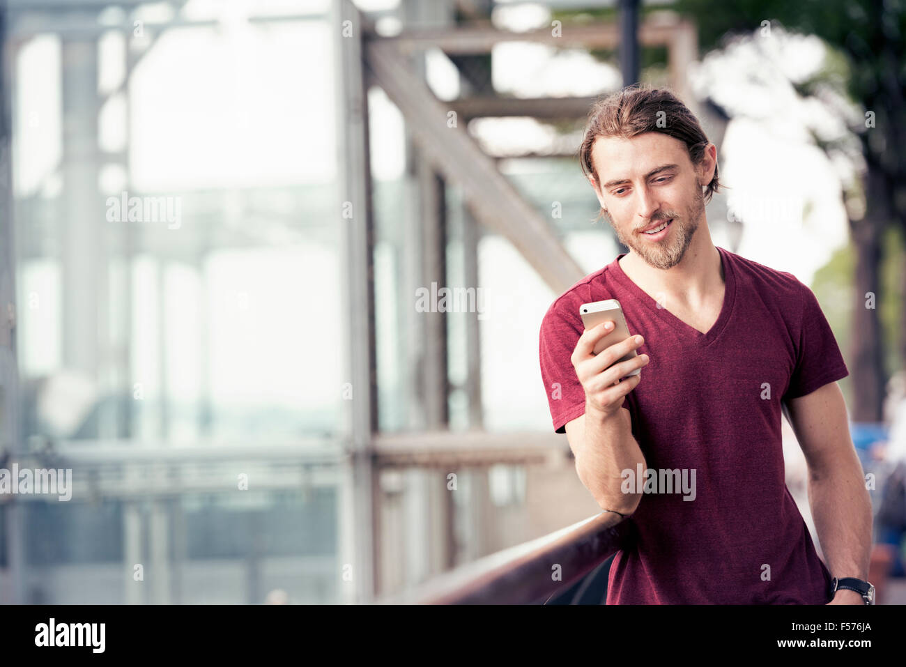 A young man leaning on a park railing checking his cell phone Stock ...