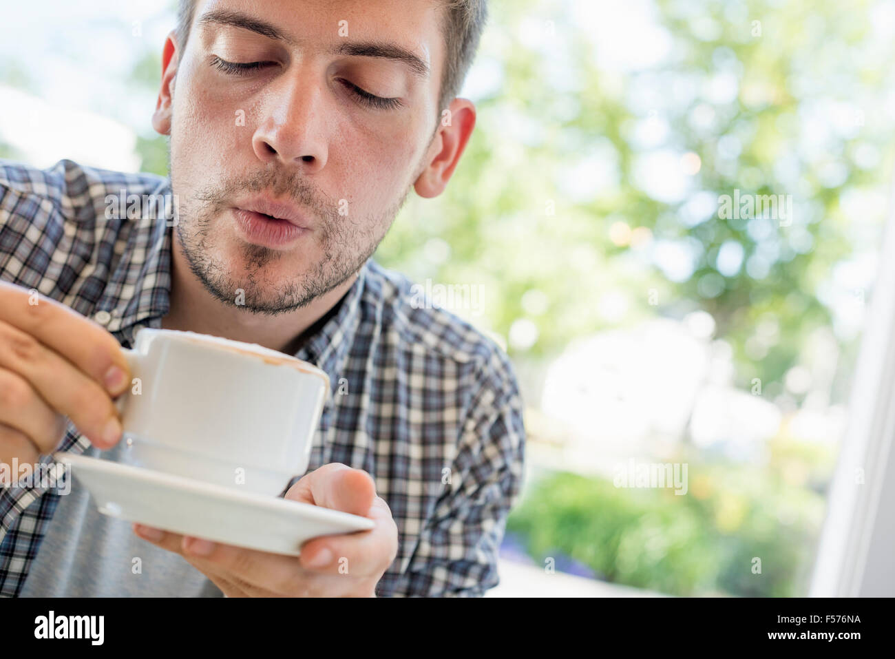 A man blowing on the surface of his hot coffee Stock Photo - Alamy
