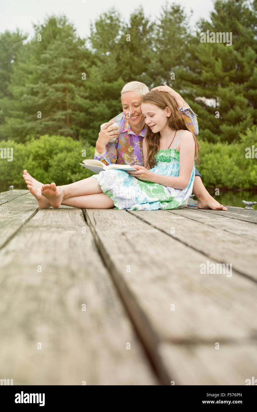 A young child with an open book on her lap, reading beside a mature ...