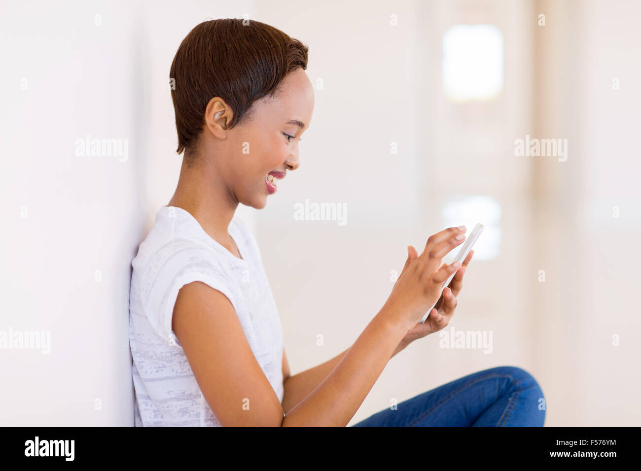 side view of happy young African girl texting on cell phone Stock Photo ...