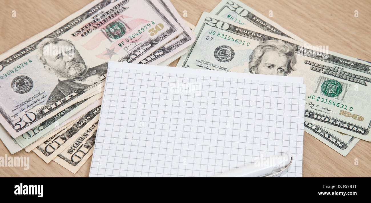 Various dollar notes next to notepad on desk Stock Photo - Alamy