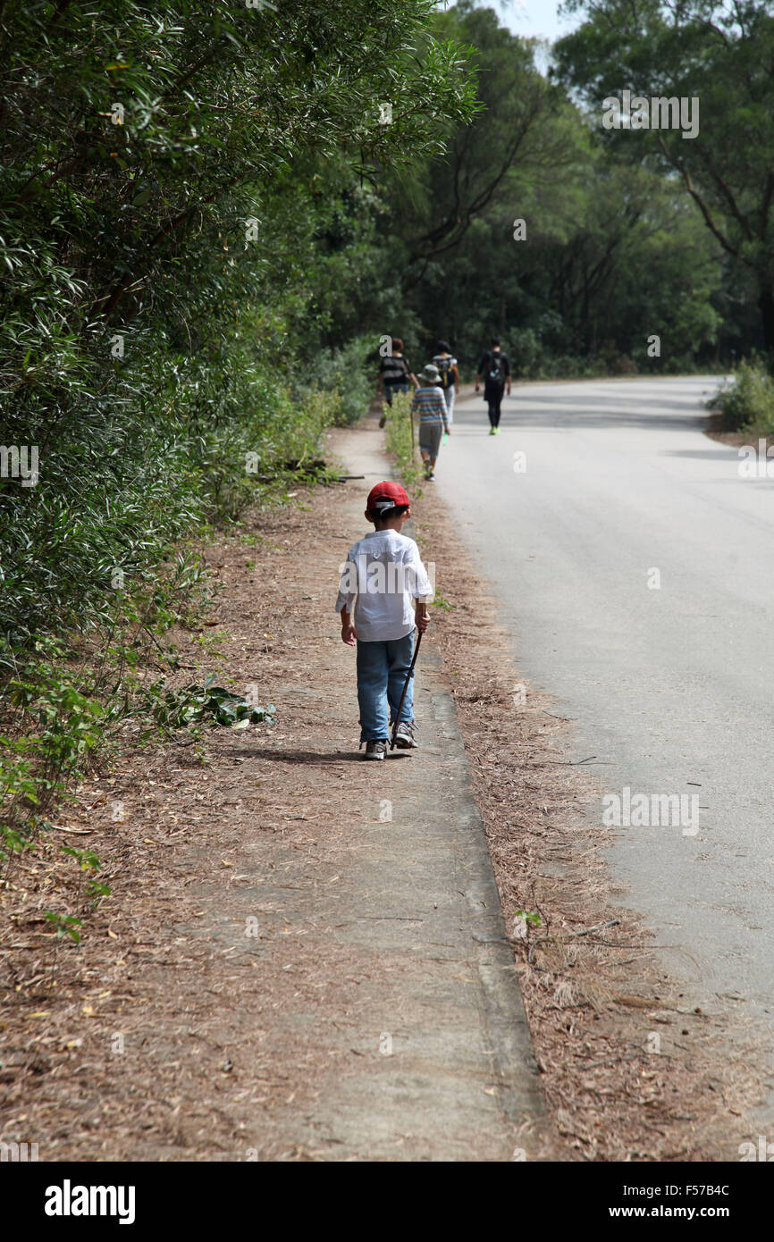 It's a photo of a child walking on the pavement along the road. We see ...