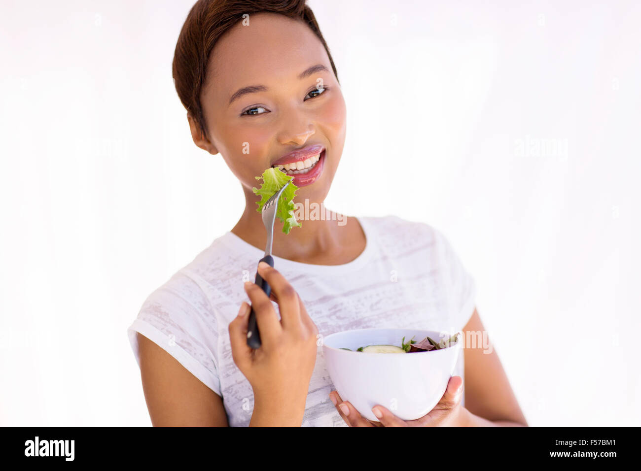 close up portrait of healthy young African woman eating green salad at ...