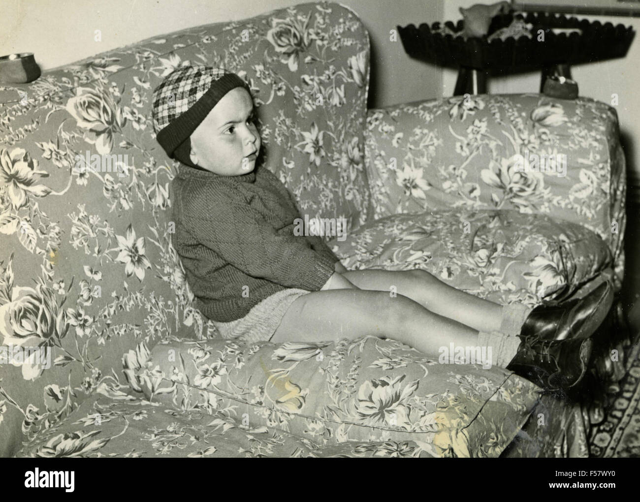 A sulky child sitting on the couch, Italy Stock Photo - Alamy