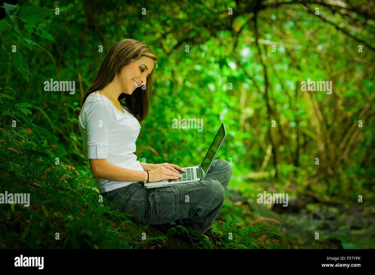 Beautiful young girl using laptop outdoors in the wild enjoying ...