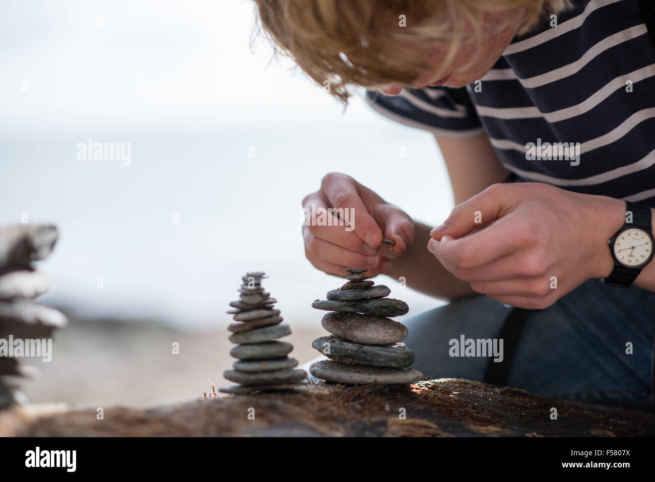 Teenage blond-haired boy concentrating on carefully balancing tiny ...