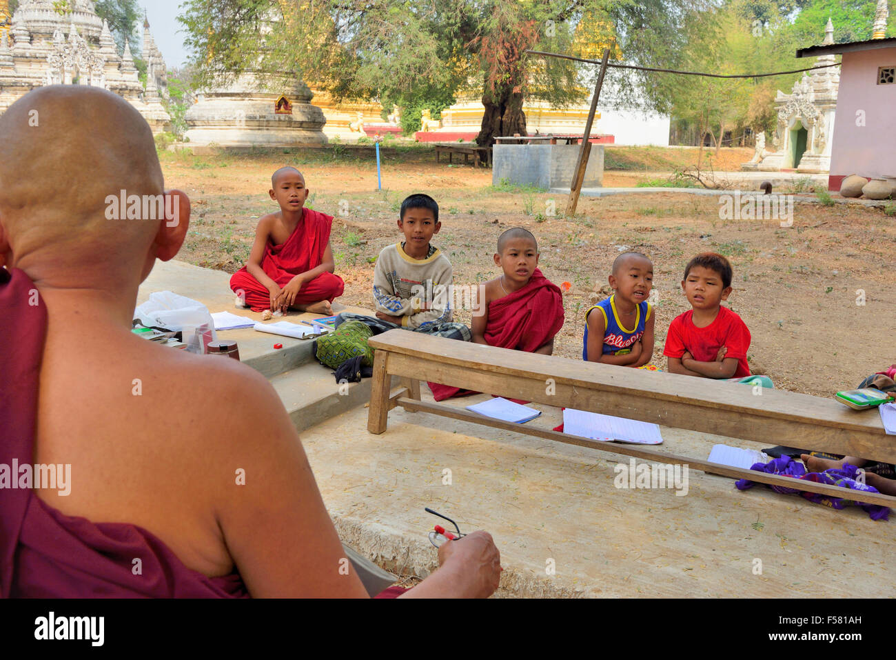 Buddhist Monk teaching schoolchildren lessons outdoors in the grounds ...