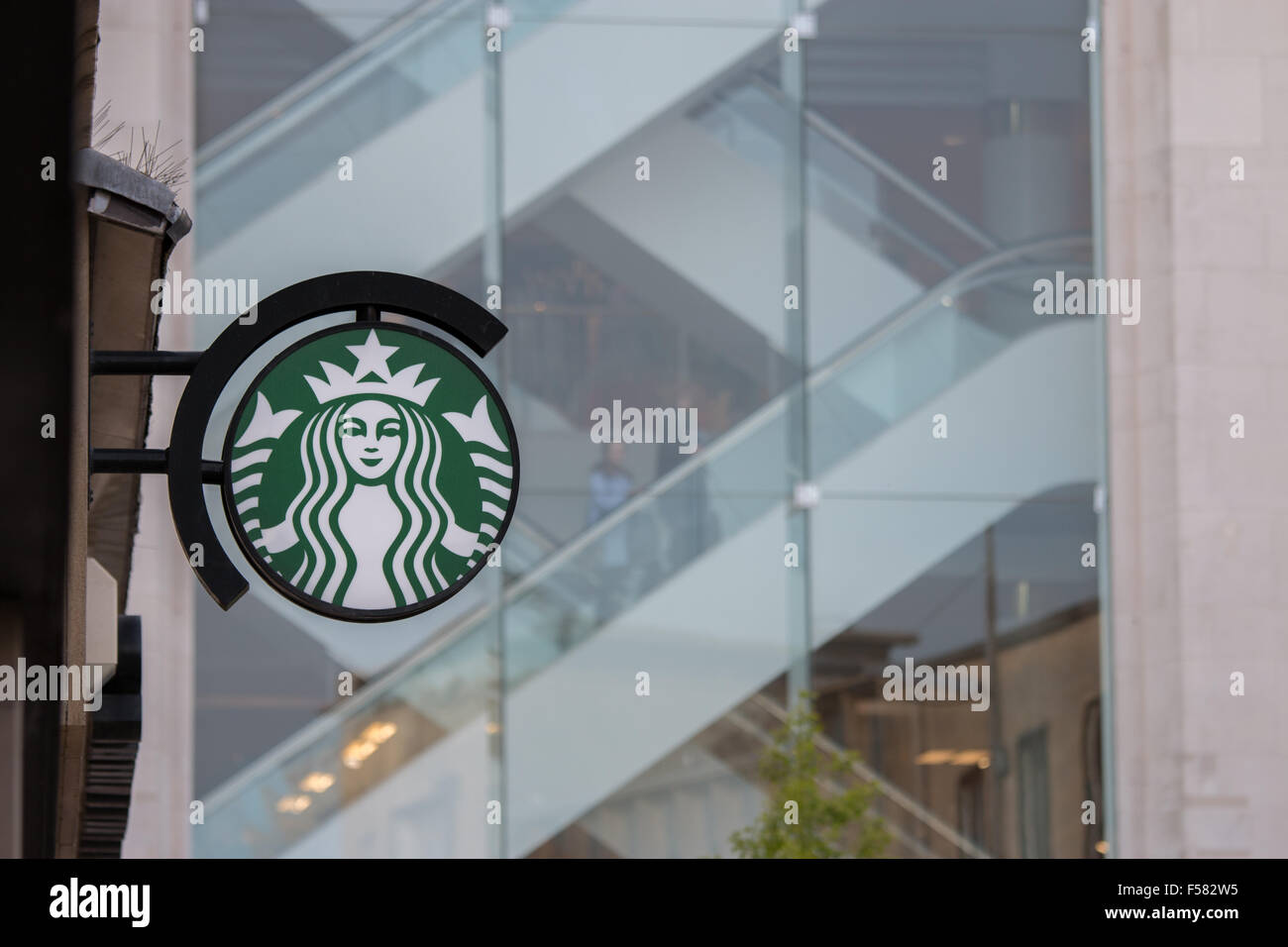 Starbucks logo outside a starbucks, with a window and escalator behind ...