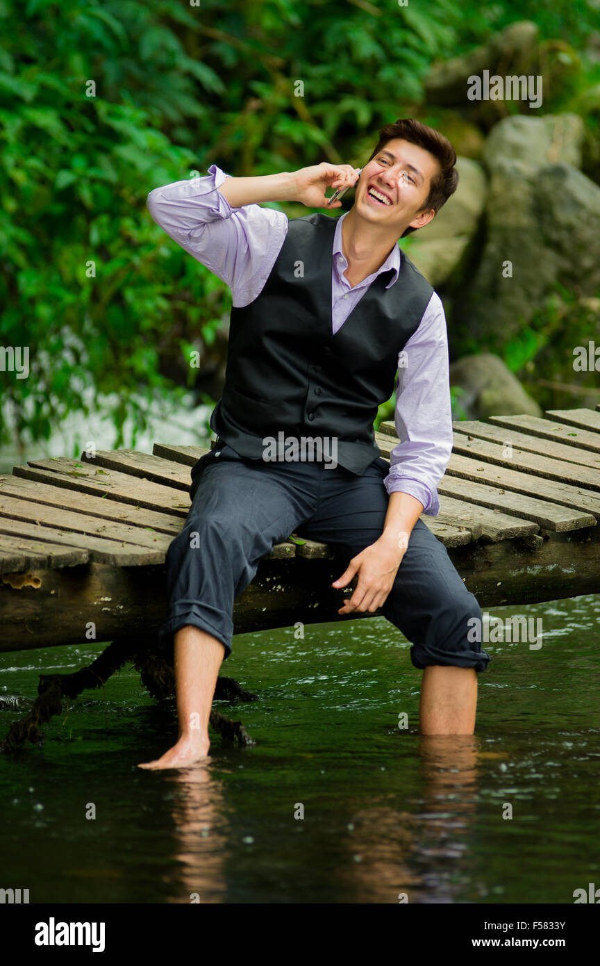 Elegant young man using cell phone in a lake Stock Photo - Alamy