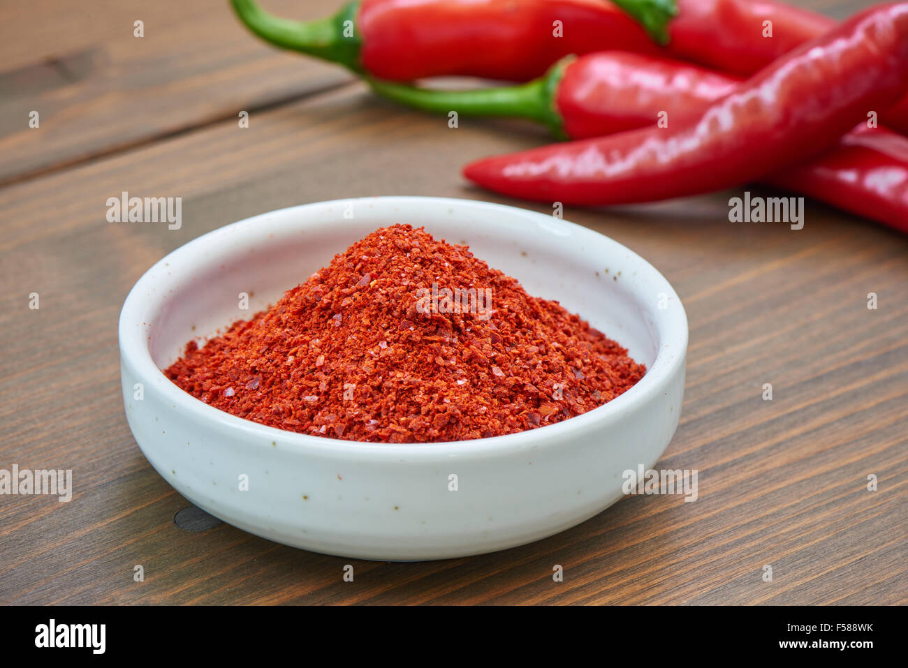 closeup of Korean chili pepper powder with chili peppers on a wooden ...